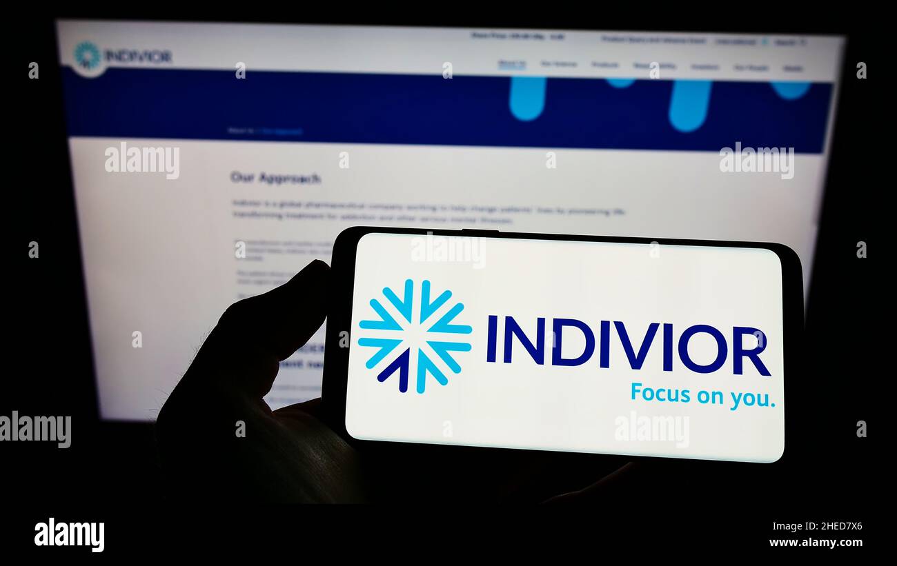 Person holding mobile phone with logo of British pharmaceutical company ...