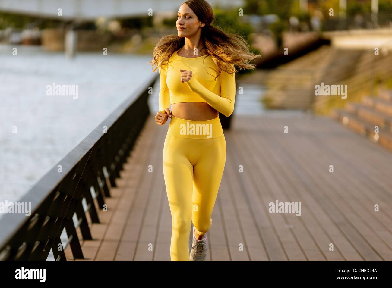 Pretty young woman running exercise on the riverside pier Stock Photo ...