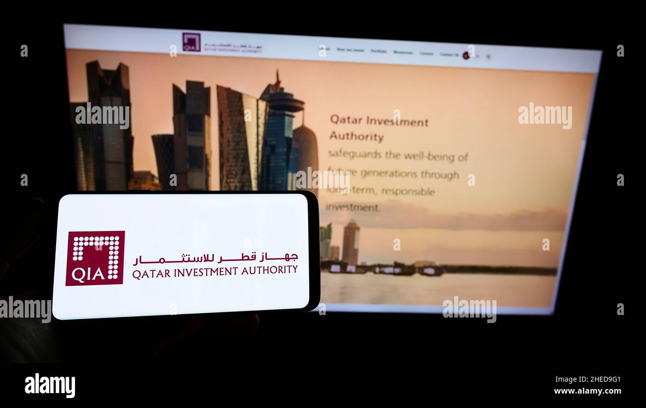 Person holding smartphone with logo of wealth fund Qatar Investment ...