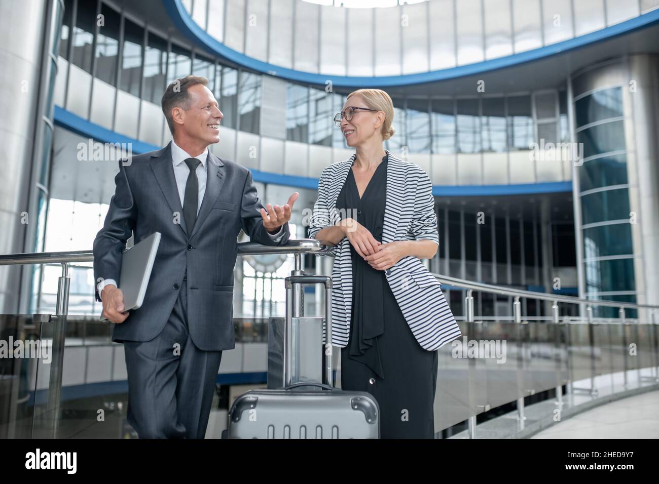 Two smiling entrepreneurs standing at the airport terminal Stock Photo ...