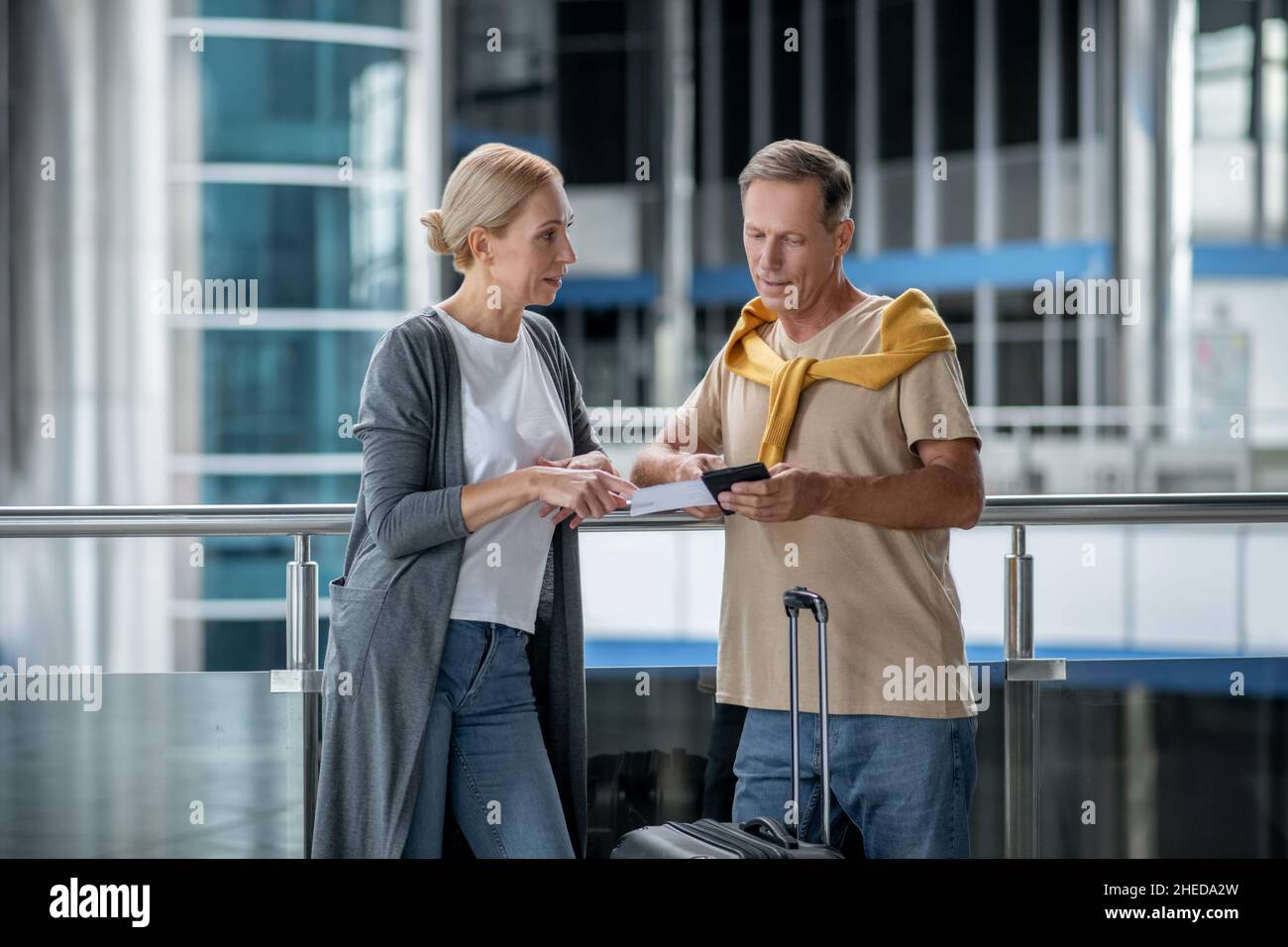 Airport passenger talking to a male with travel documents Stock Photo ...
