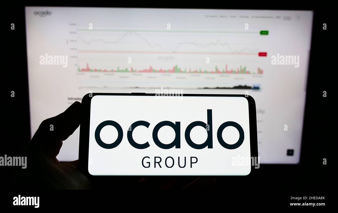 Person holding mobile phone with logo of British retail company Ocado ...
