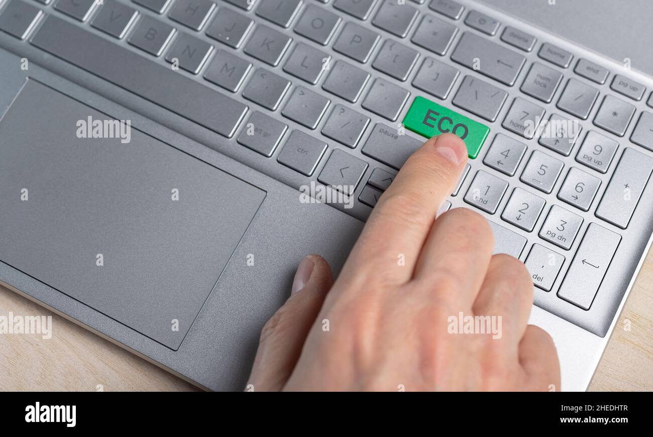 Laptop and eco-friendly technology concept. Hand pressing green button ...