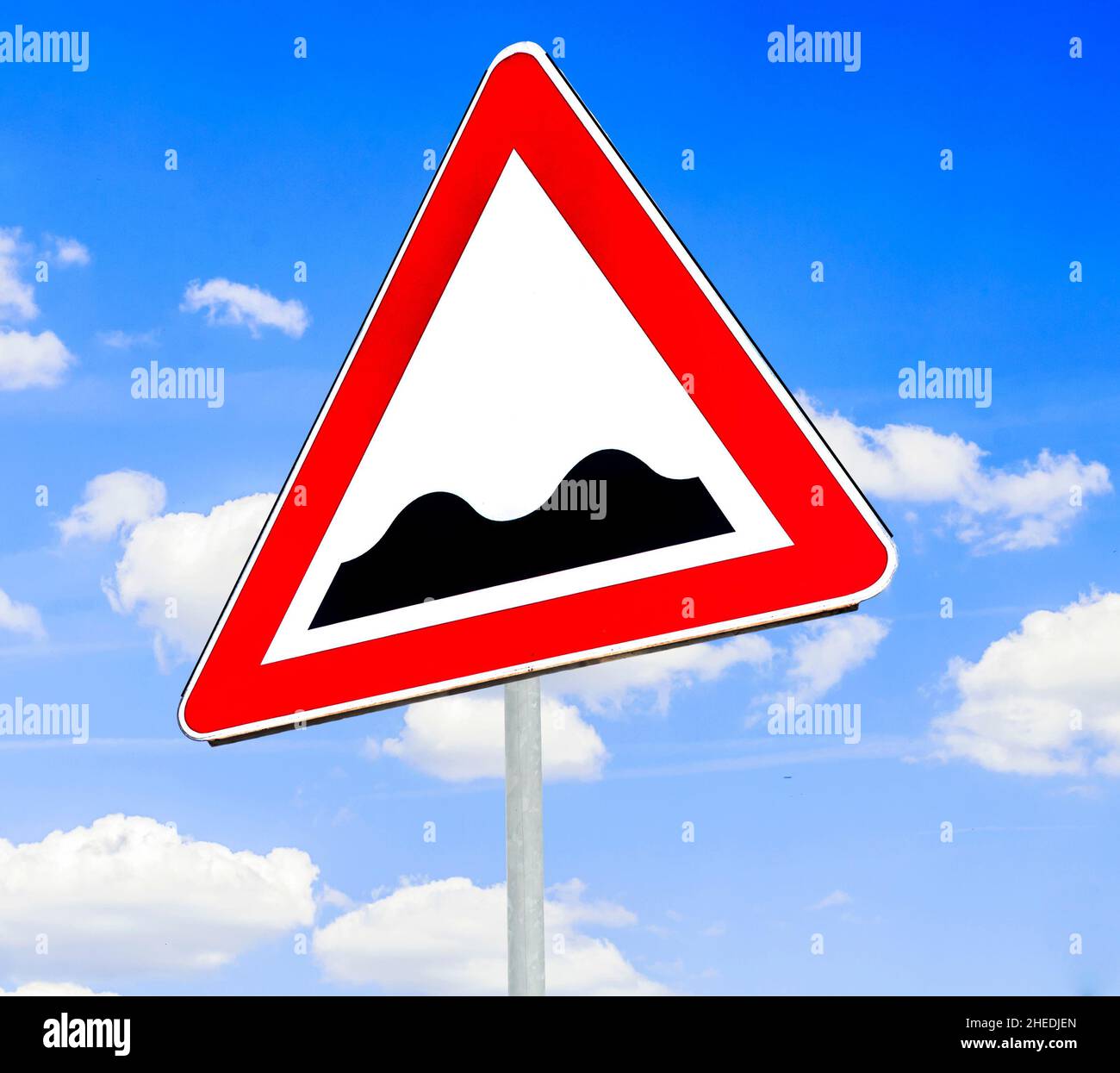 Red and white triangular warning road sign with a warning of a bumpy road ahead Stock Photo - Alamy