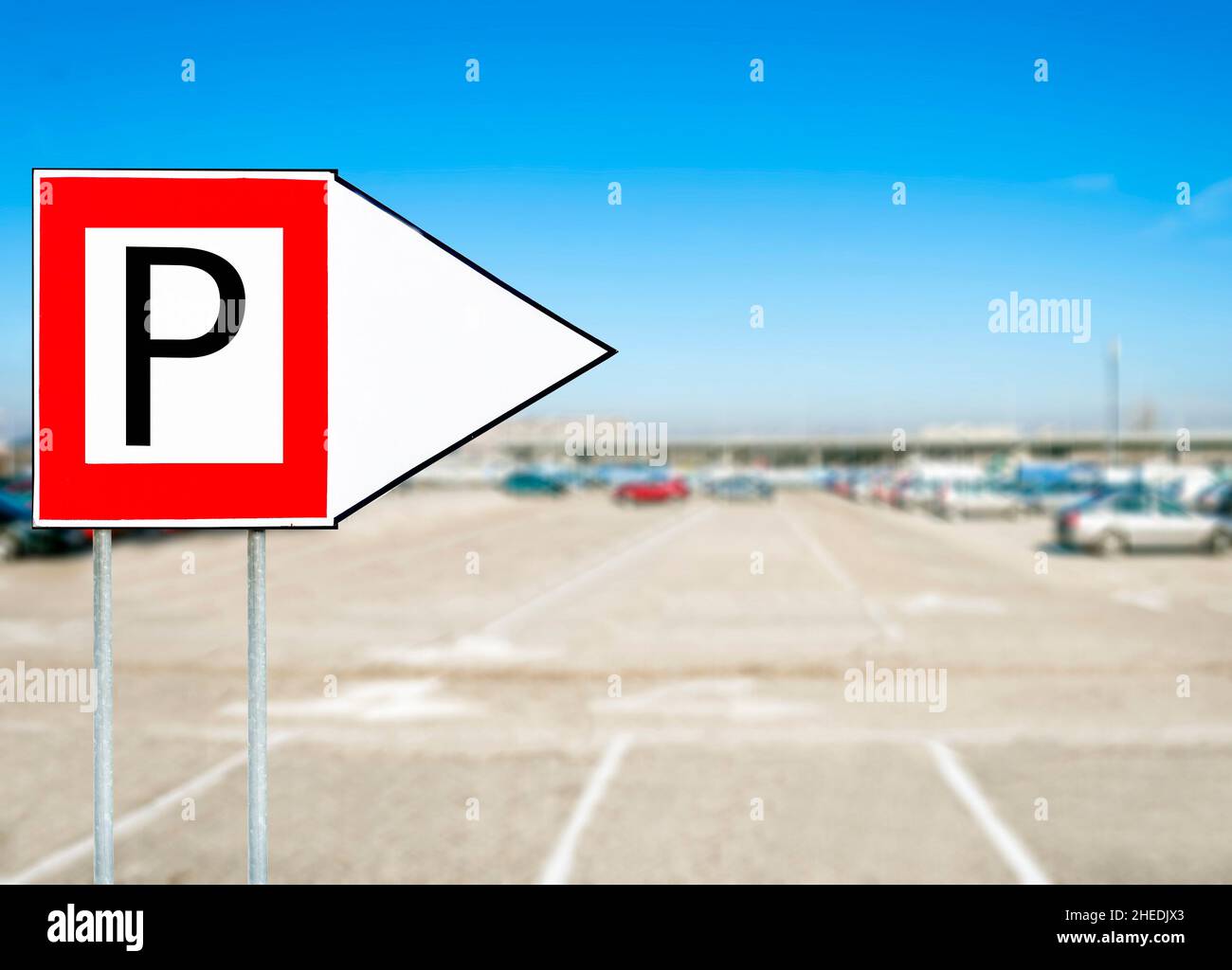 Red parking sign with arrow pointing with blurred cars at the ...