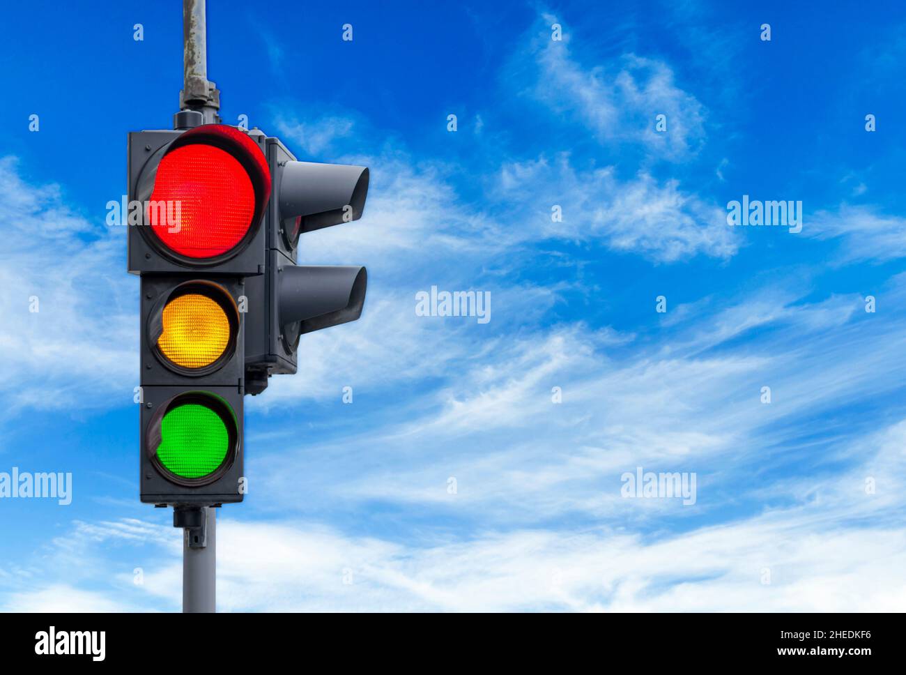 Red semaphore light with yellow and green and cloudy sky background ...