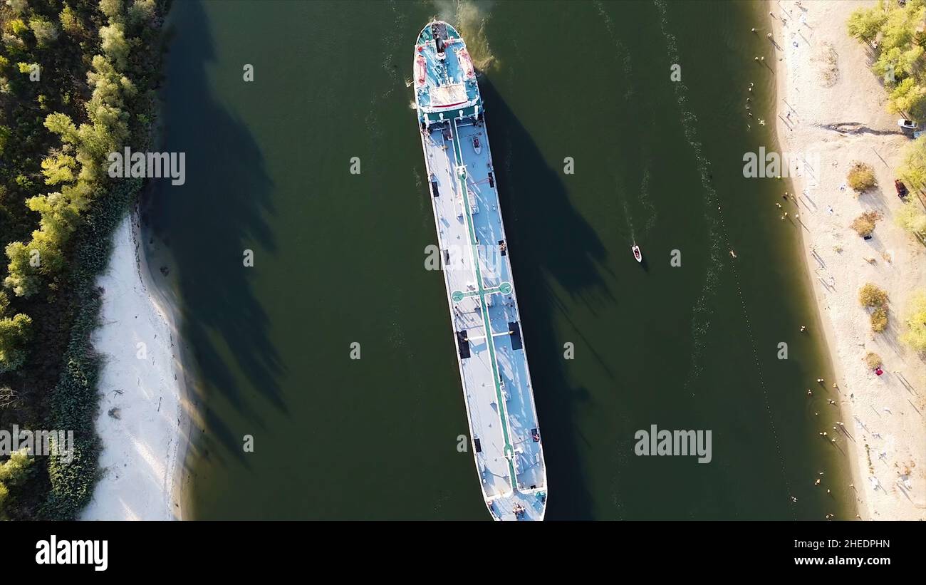 Top down view of a cargo ship in a canal of green color. Long white ...