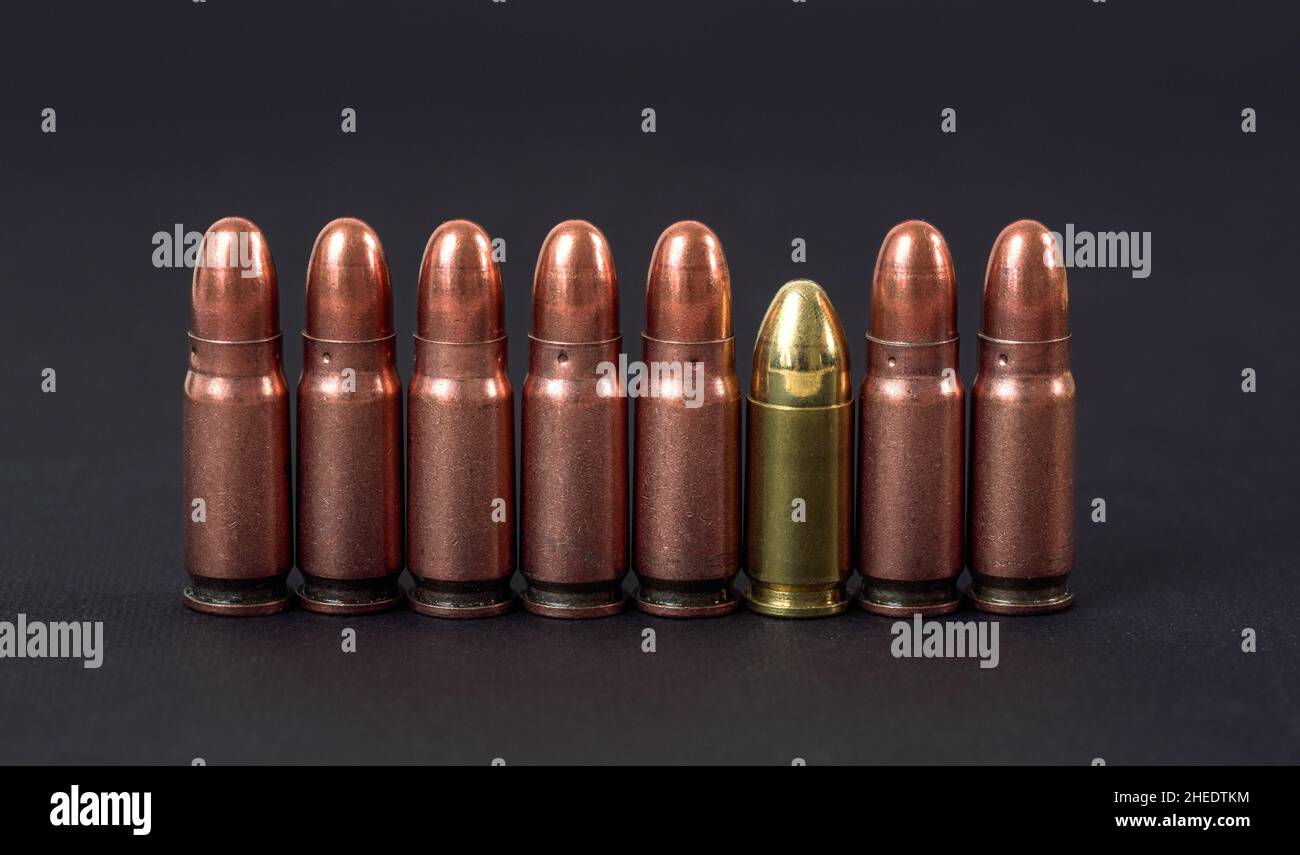 Bronze pistol bullets with one gold coloured arranged next to each ...