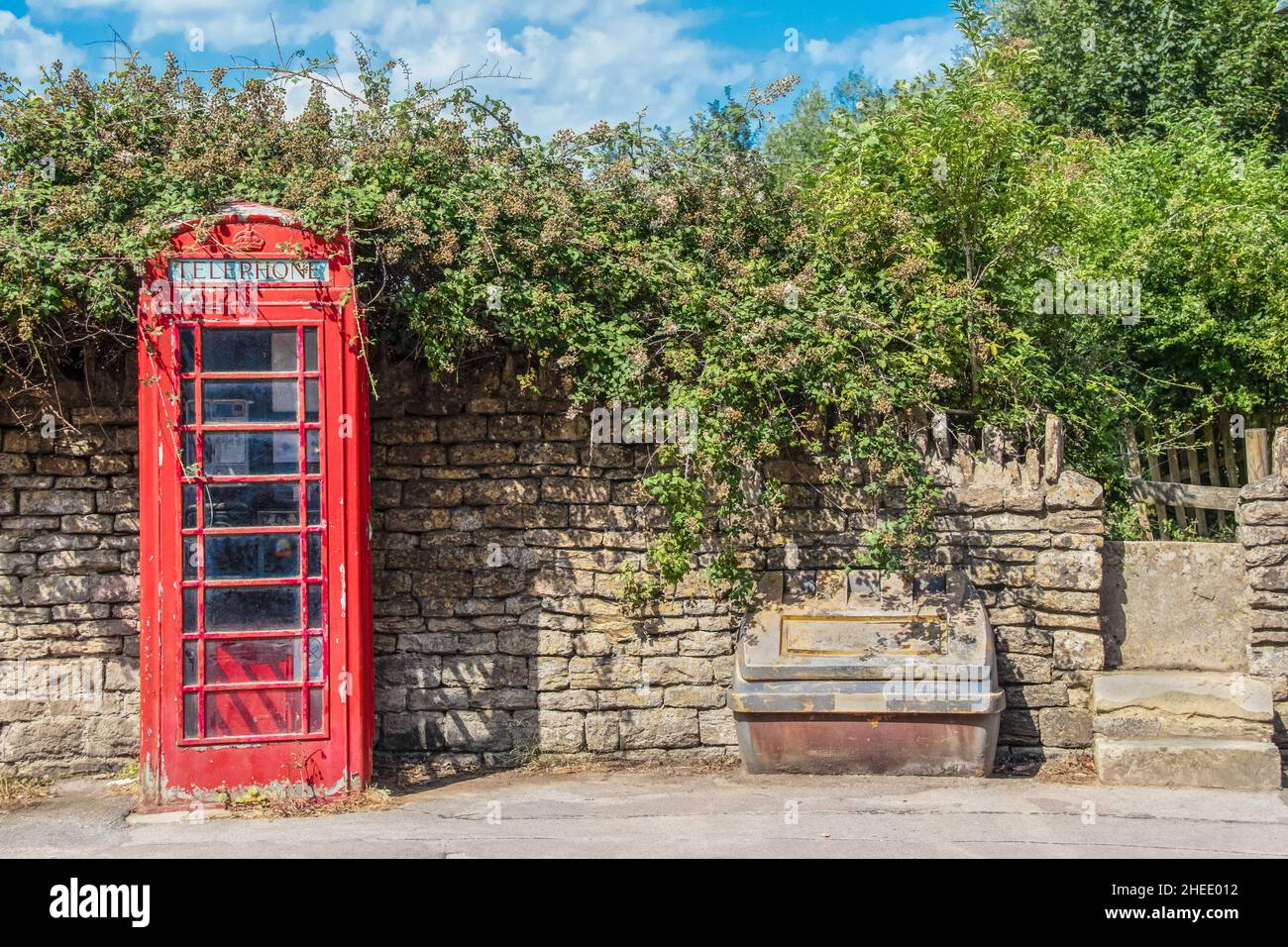 British red telephone booth by ancient rock wall with vines growing ...