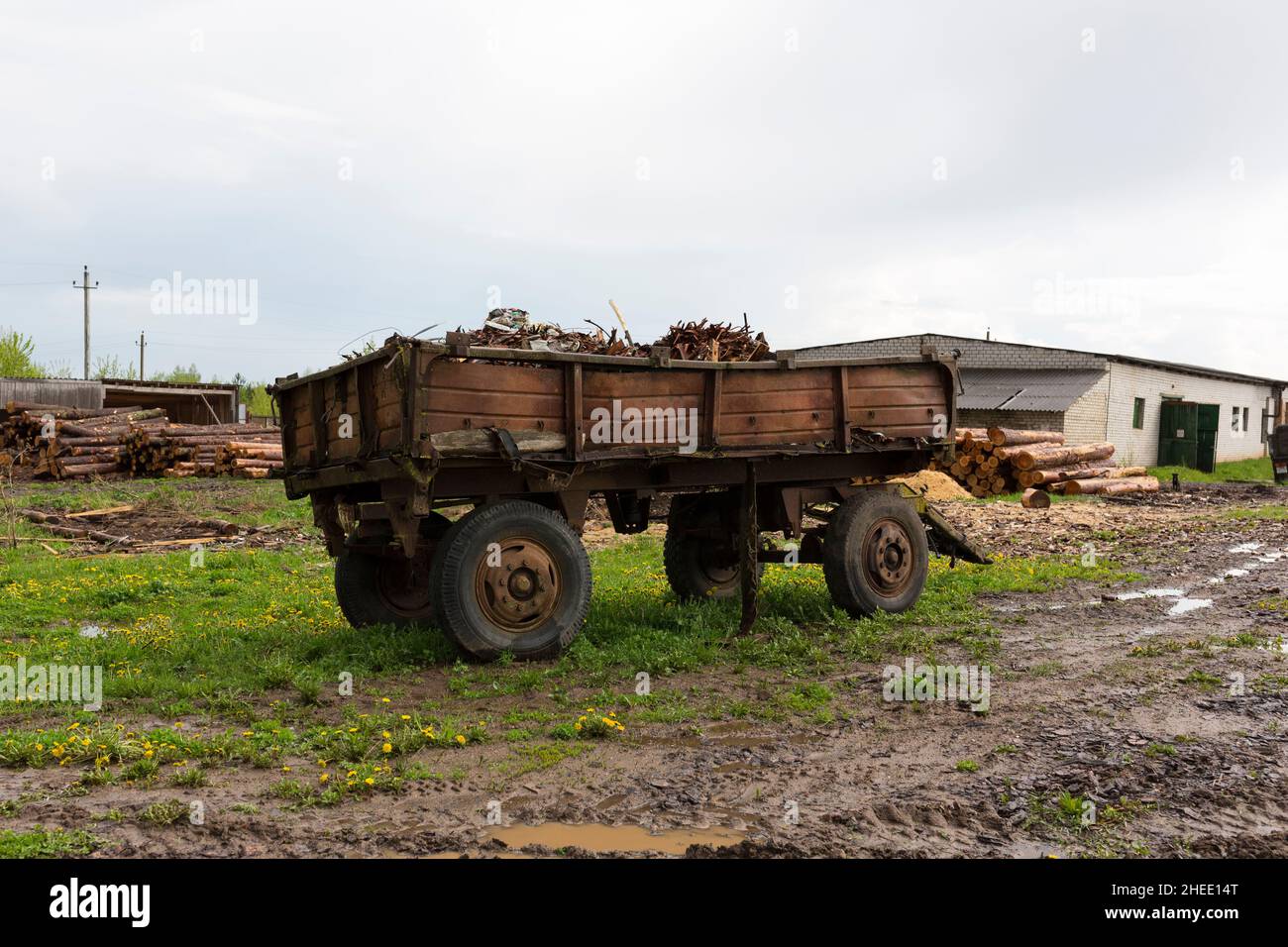 Old abandoned rusty tractor trailer. Stands on a green lawn in a muddy ...