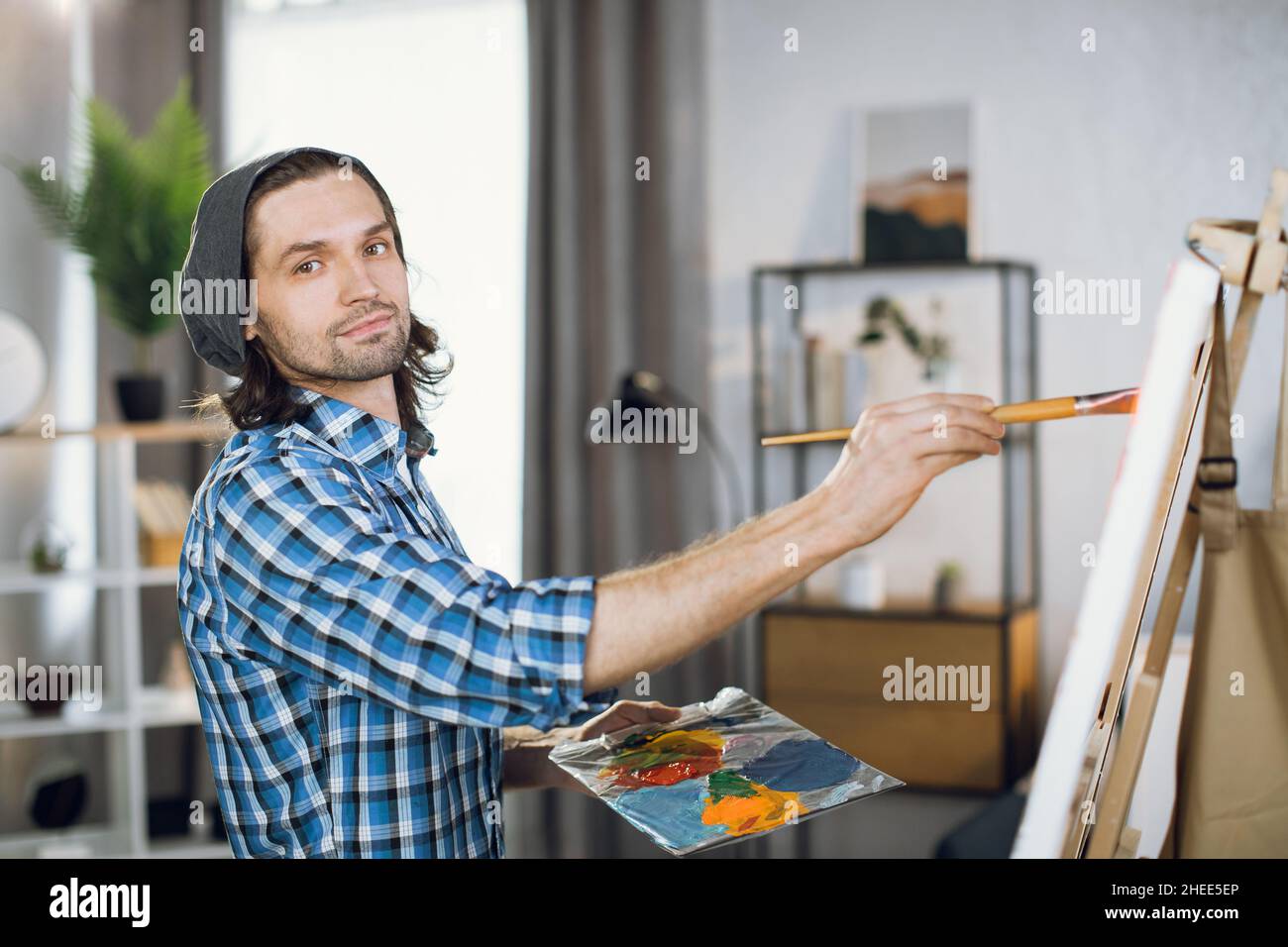 Happy male artist winking and smiling on camera while drawing with ...