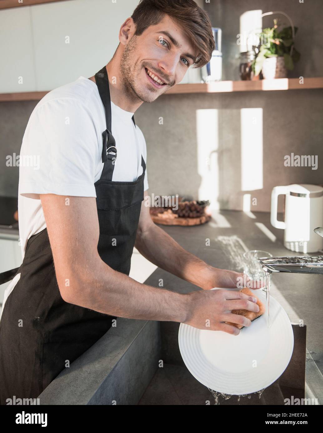 attractive young man is washing dishes in his kitchen Stock Photo - Alamy