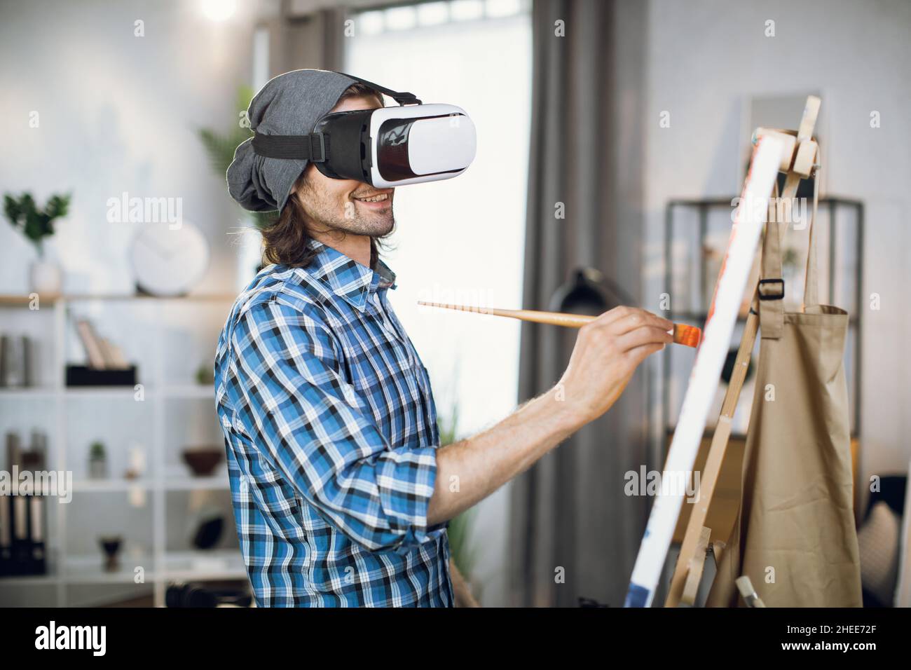 Caucasian male painter wearing VR headset while painting with brush on ...