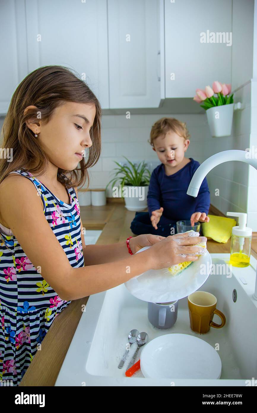 Children wash dishes in the kitchen. Selective focus Stock Photo - Alamy