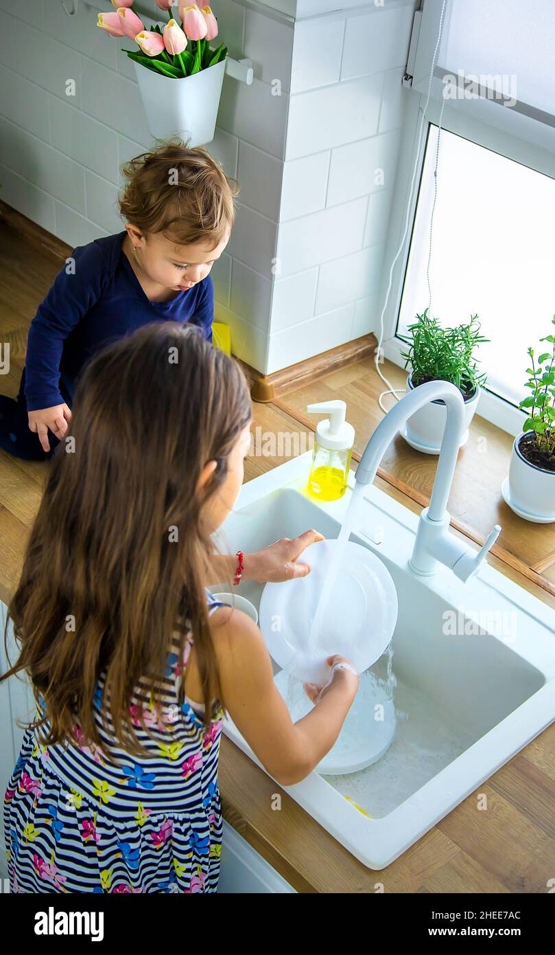 Children wash dishes in the kitchen. Selective focus Stock Photo - Alamy