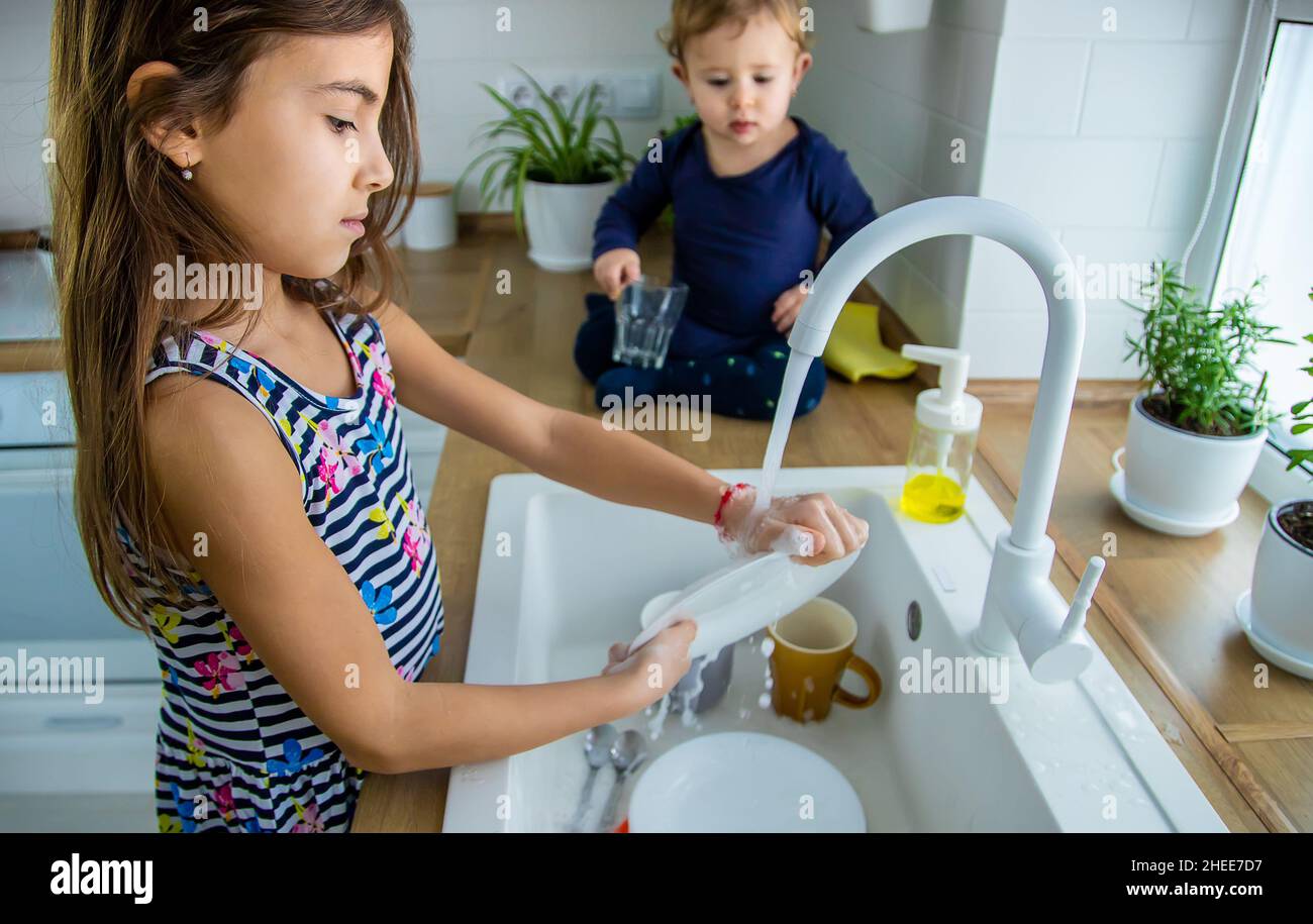 Children wash dishes in the kitchen. Selective focus Stock Photo - Alamy