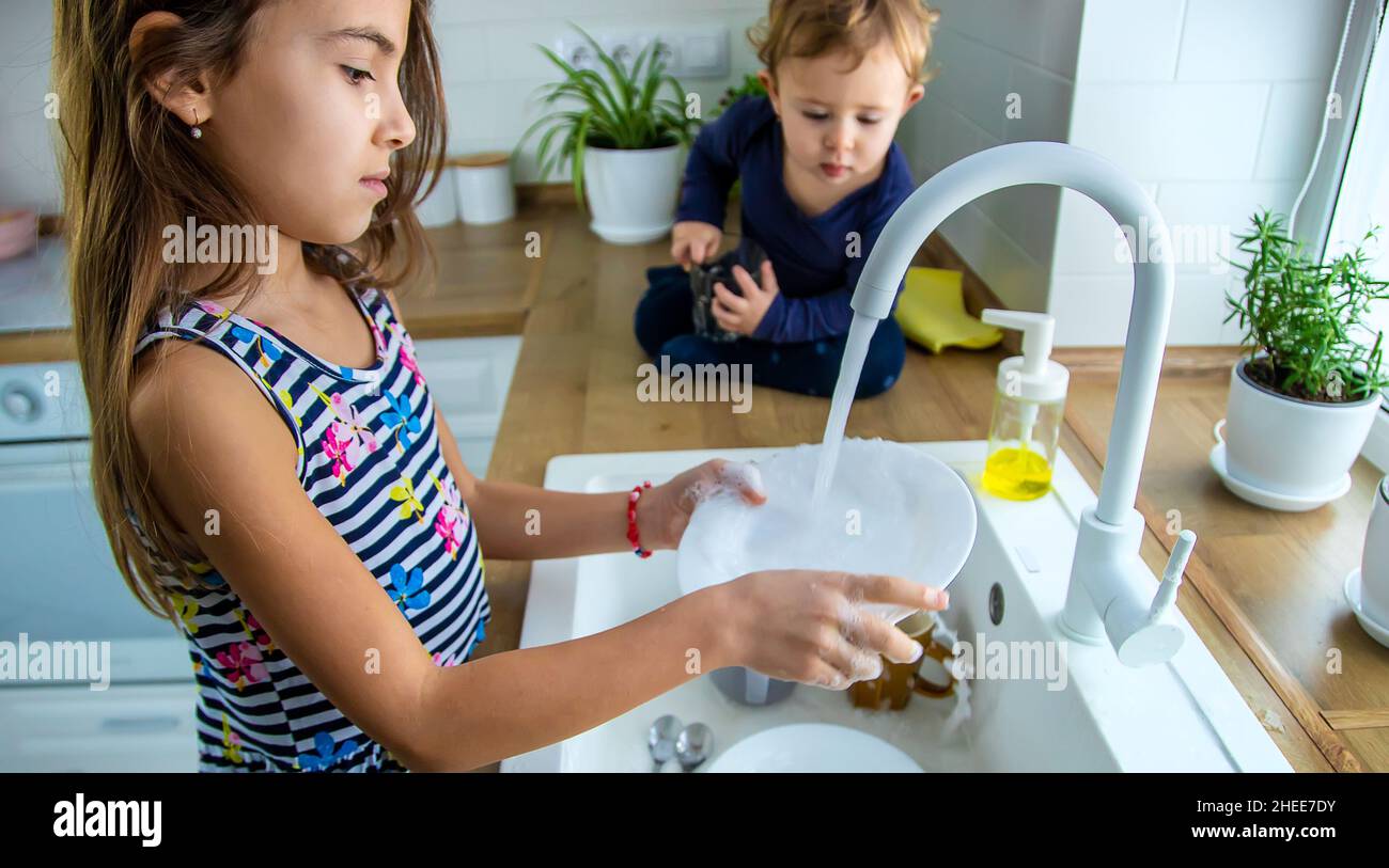 Children wash dishes in the kitchen. Selective focus Stock Photo - Alamy