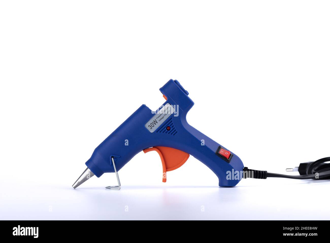 Side view of an electric hot glue gun on a white background. Blue glue ...