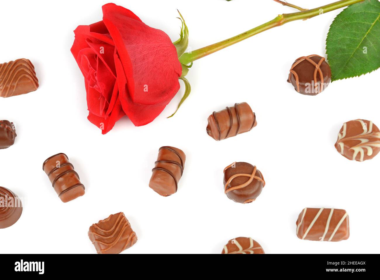 Assortment of chocolate candies and red rose isolated on white ...