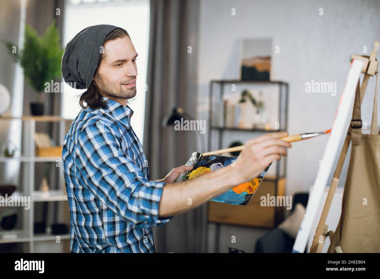 Handsome caucasian man drawing with brush on canvas at his painting ...