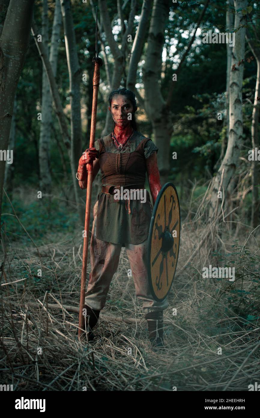 Full body of brave female in viking costume standing with spear and ...