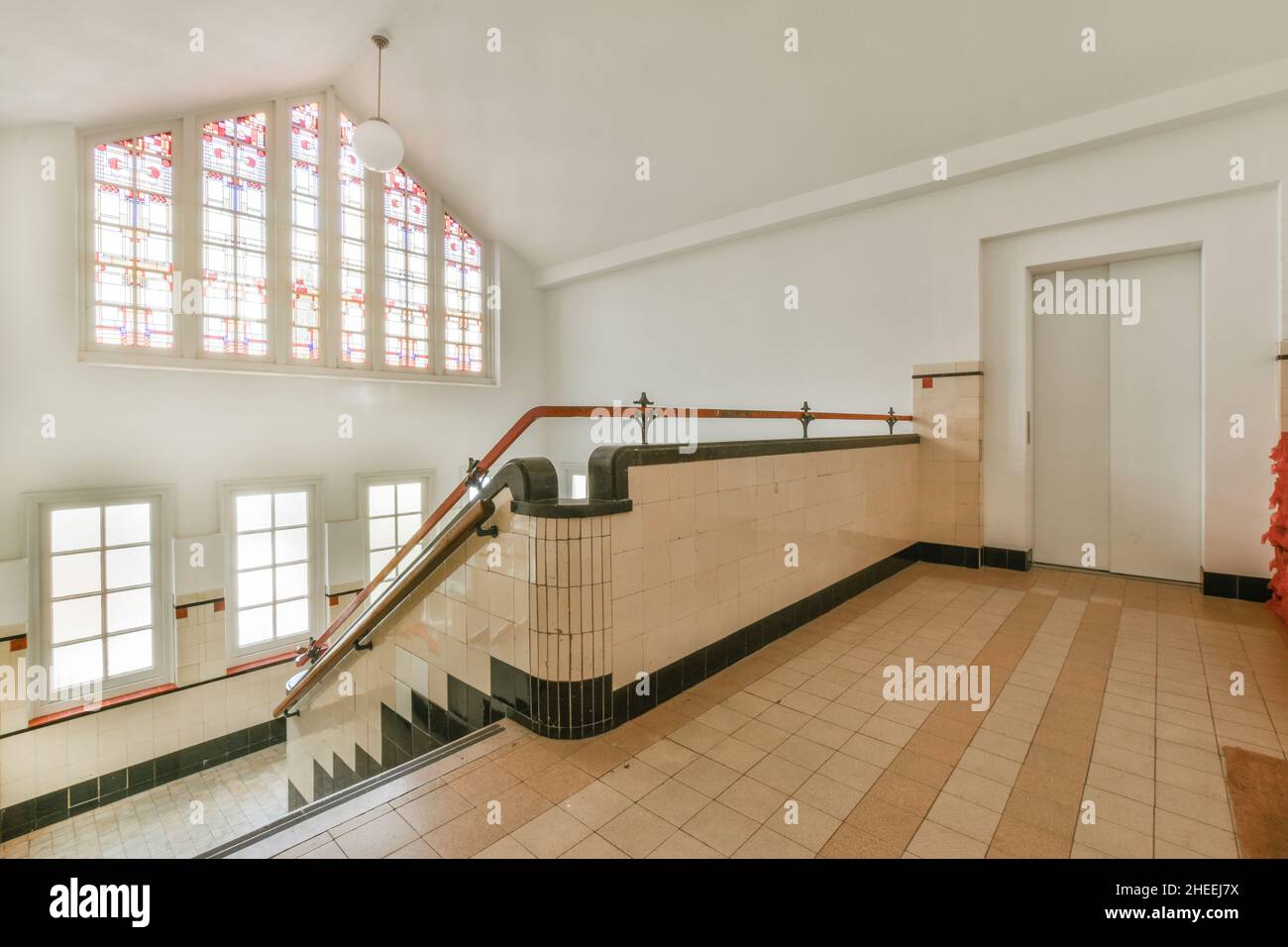 Interior of spacious hall with tiled walls and floor and staircase with ...