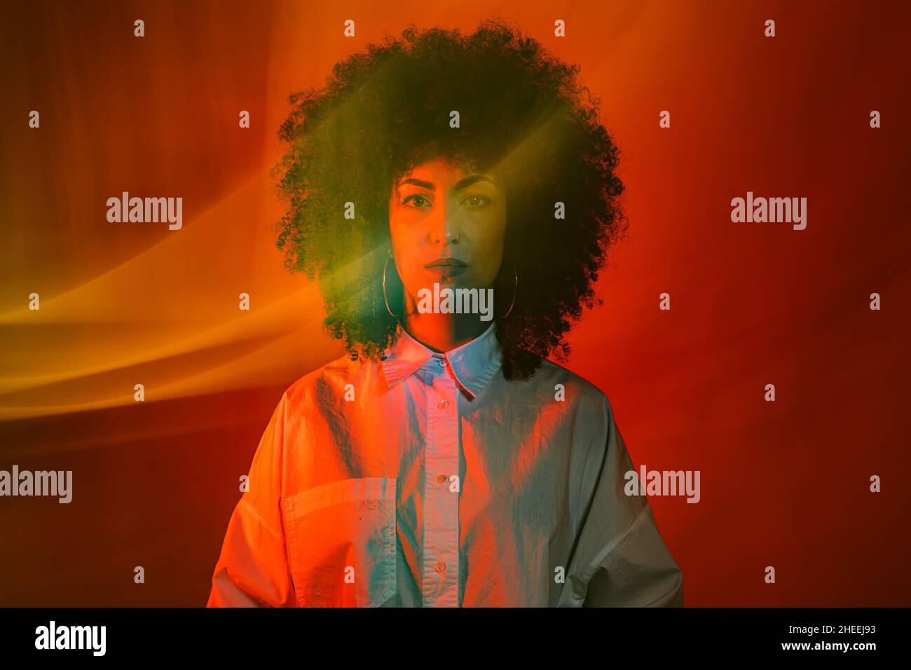 Unemotional young ethnic female model with dark Afro hair in white ...