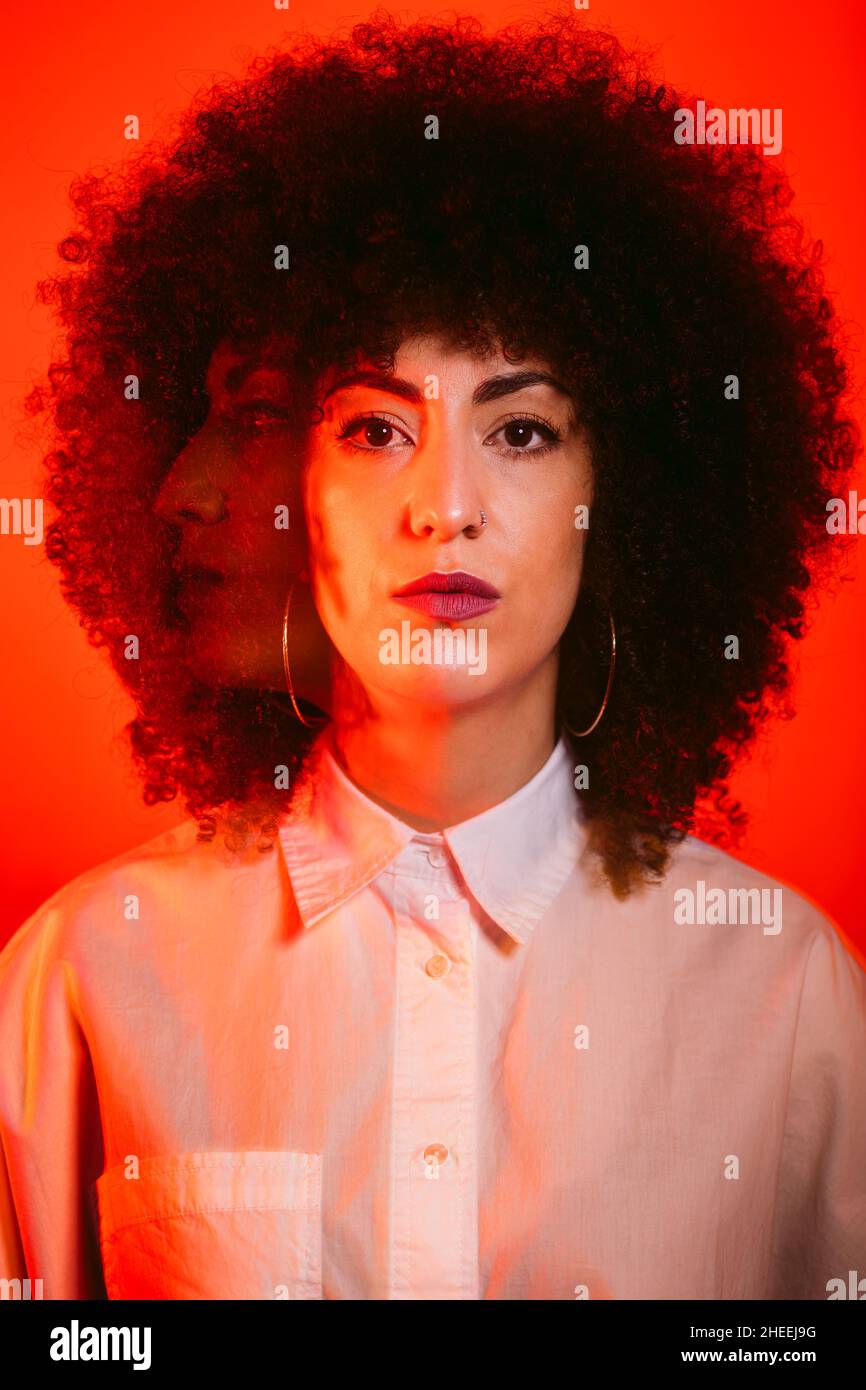 Unemotional young ethnic female model with dark Afro hair in white ...