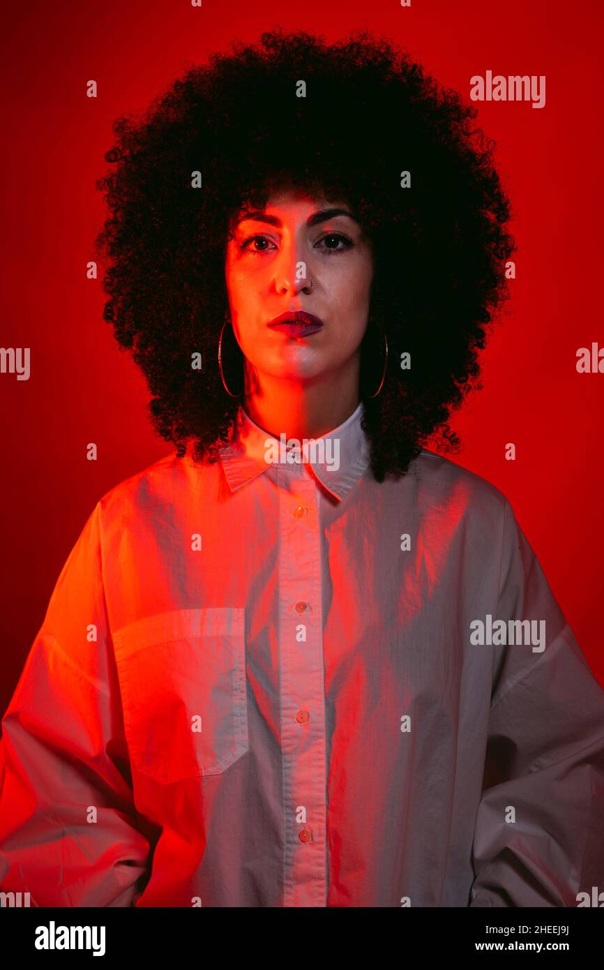 Unemotional young ethnic female model with dark Afro hair in white ...