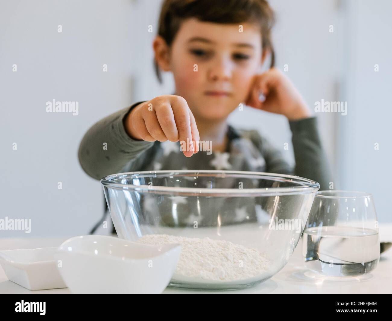 Blurred girl putting flour into glass bowl while preparing for cooking ...