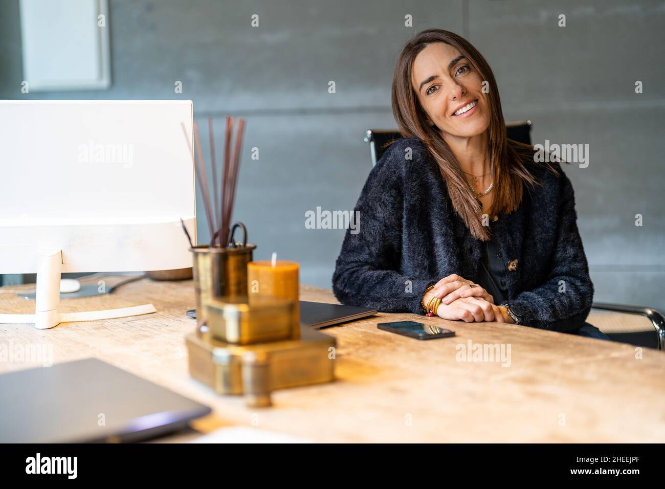 Cheerful female in stylish black outfit looking at camera while sitting ...