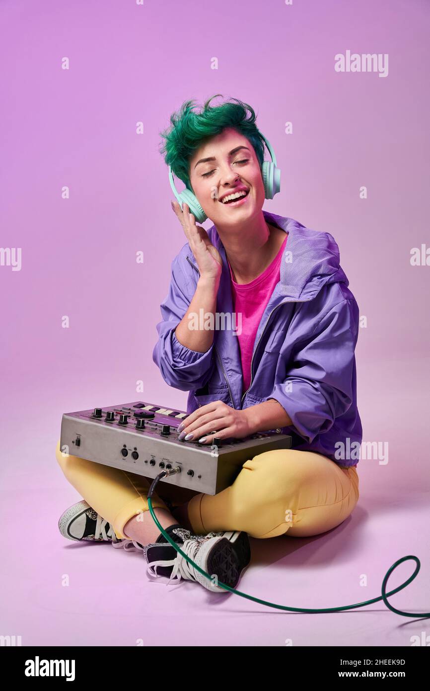 Full body of talented Woman in retro 80s wear and headphones playing ...
