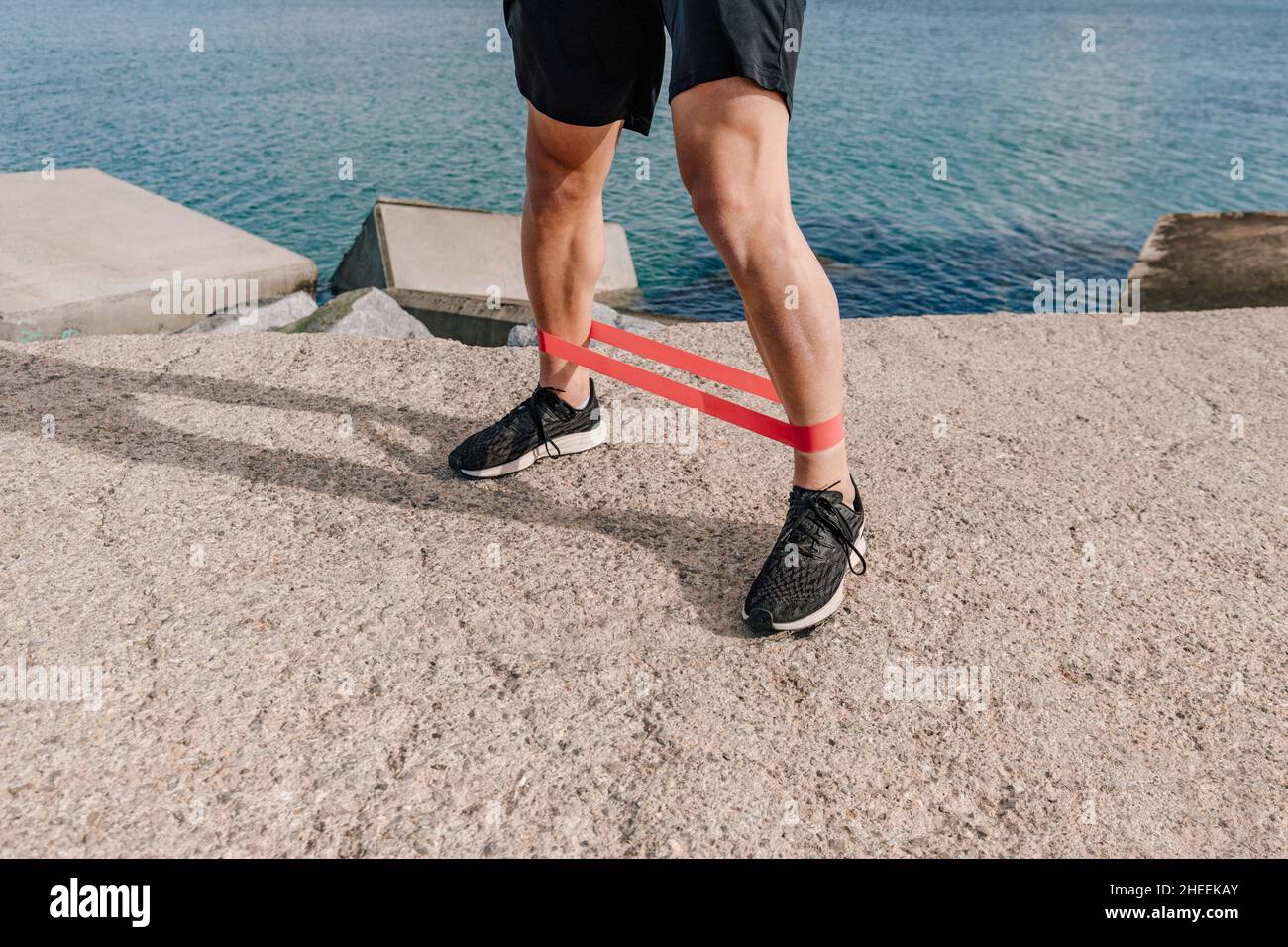 Crop anonymous sportive male in activewear practicing with resistance ...