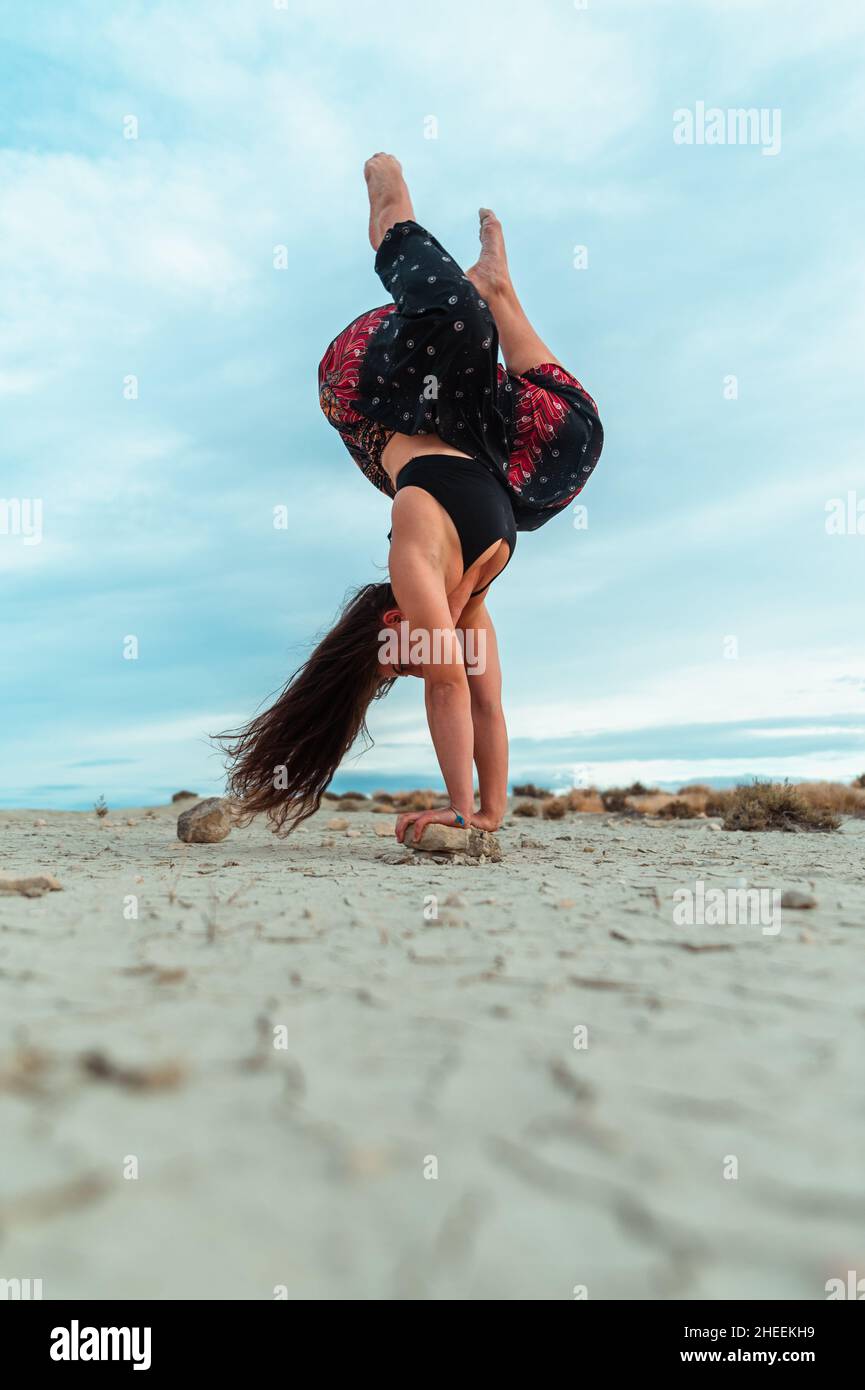 Ground level of full body of barefoot Woman doing Handstand tuck pose ...