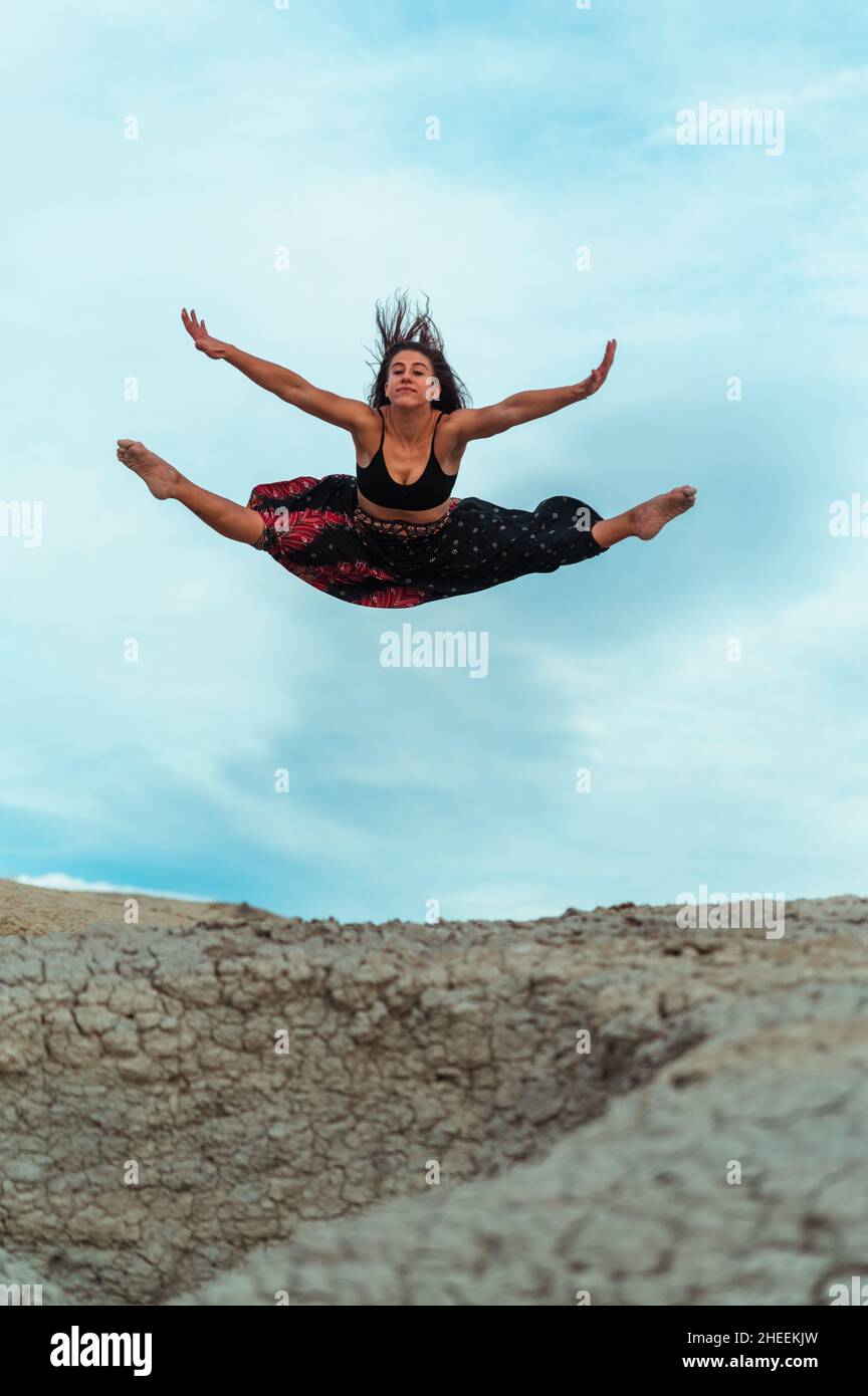 From below of full body of barefoot female jumping in split pose over ...