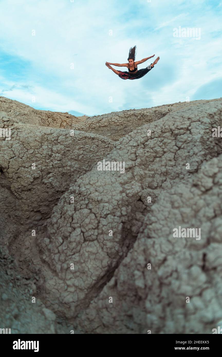 From below of full body of barefoot female jumping in split pose over ...