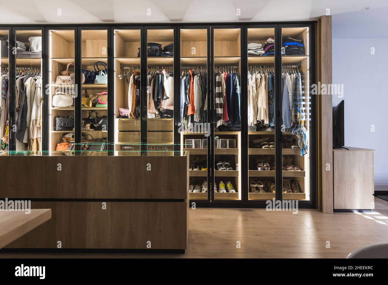 Long wardrobe with glass doors full of various clothes and accessories ...