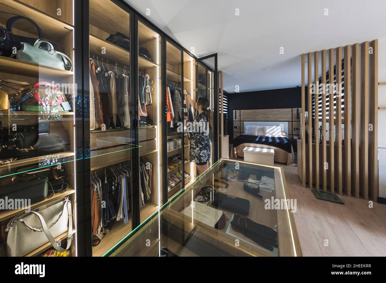 Side view of female in contemporary bedroom choosing clothes in big ...