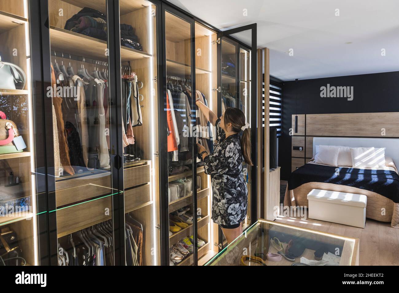 Side view of female in contemporary bedroom choosing clothes in big ...