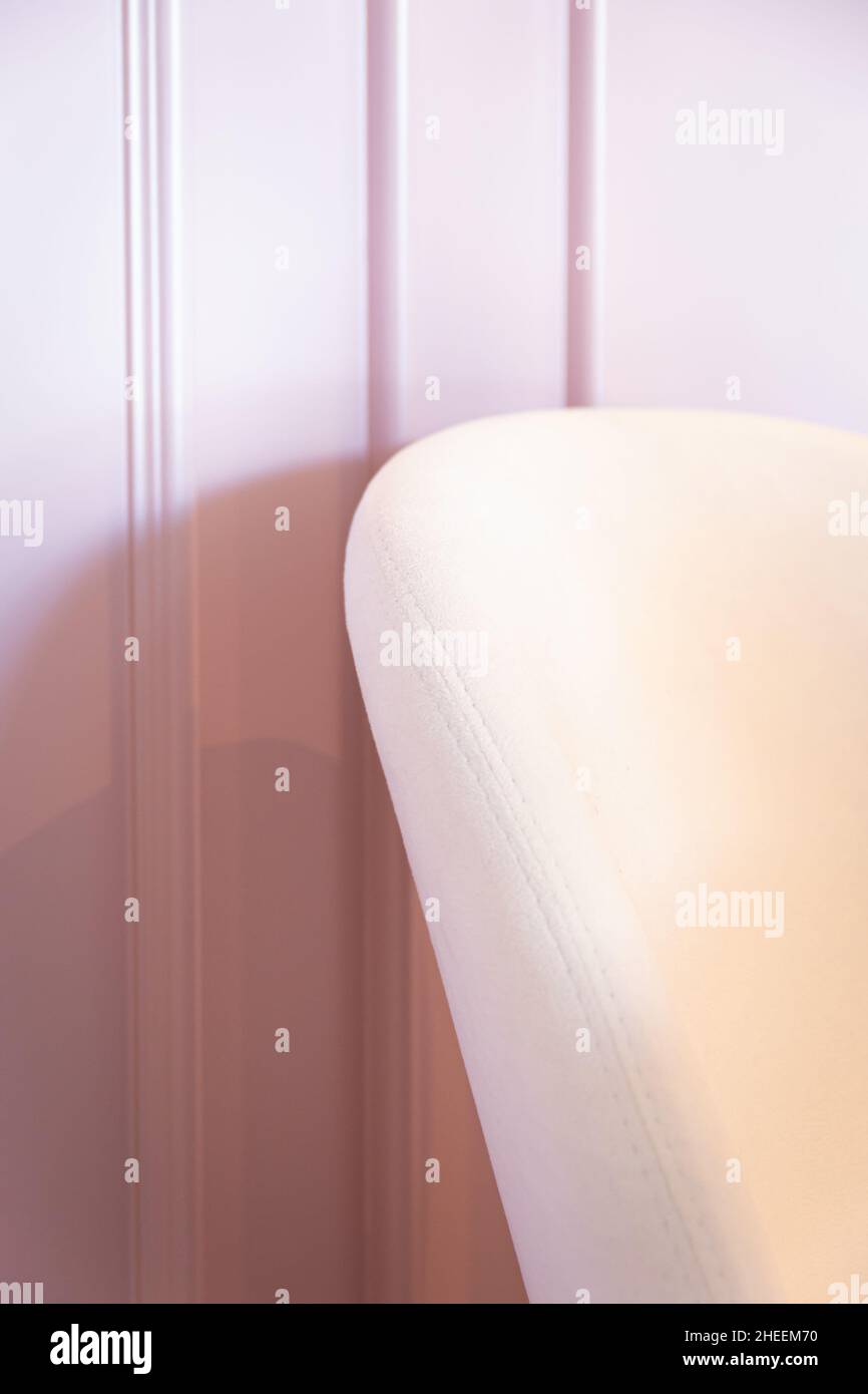 Part of white chair placed near wall parallel lines in modern apartment ...