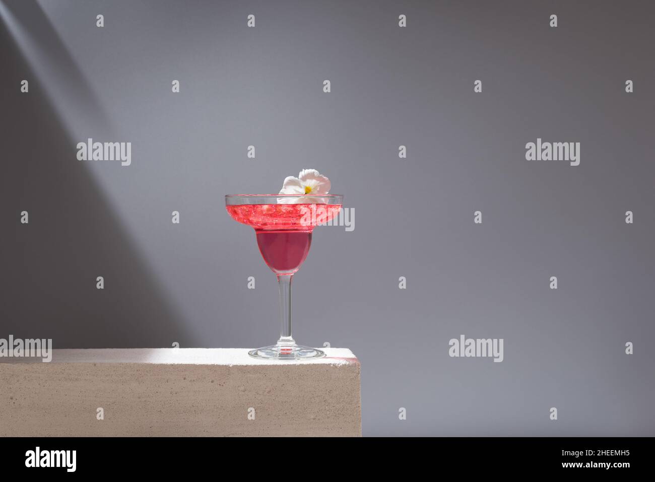 Crystal glass of pomegranate margarita cocktail served with flower ...