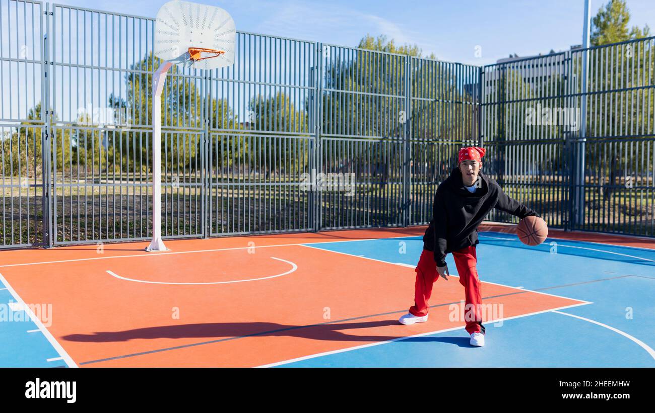 Full body of sportive Asian man in activewear dribbling ball during ...