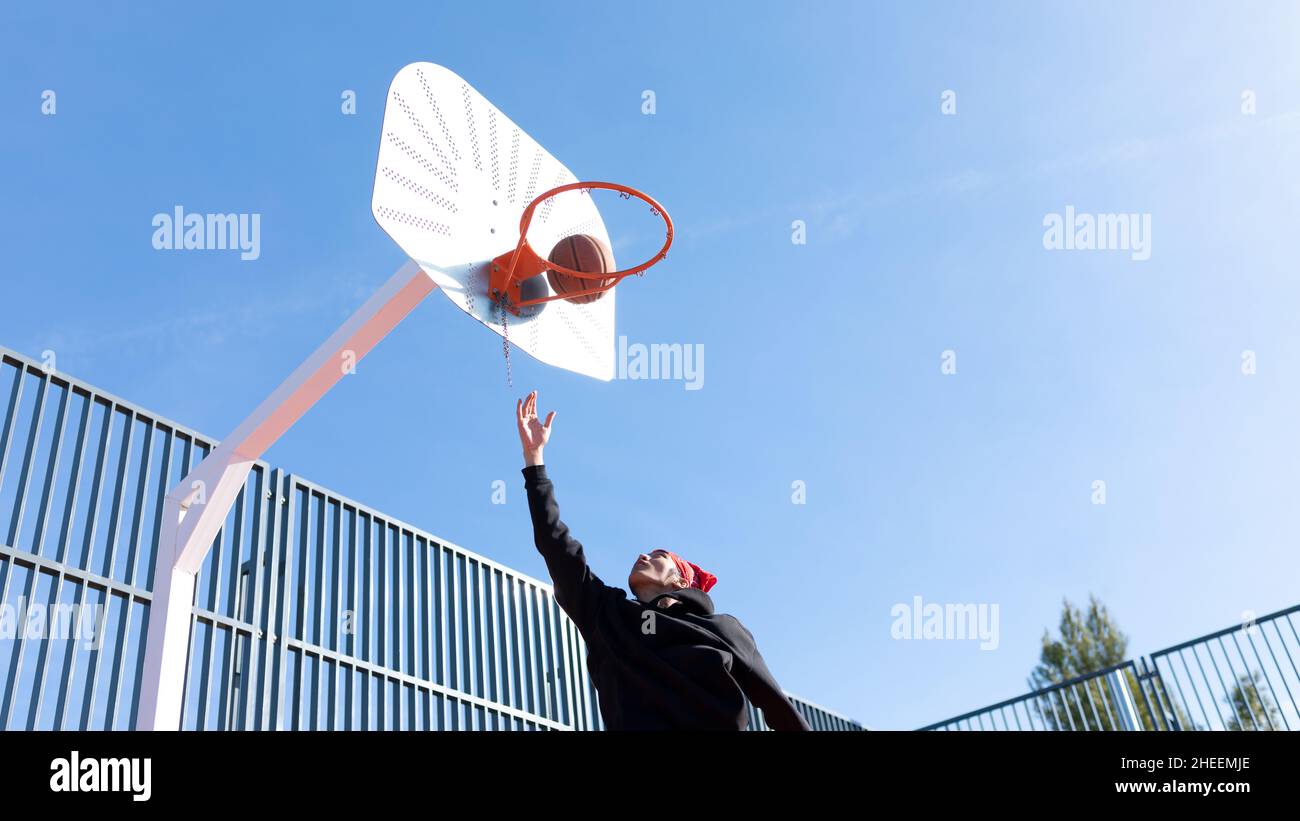 Active man throwing ball into basketball hoop with raised arm while ...