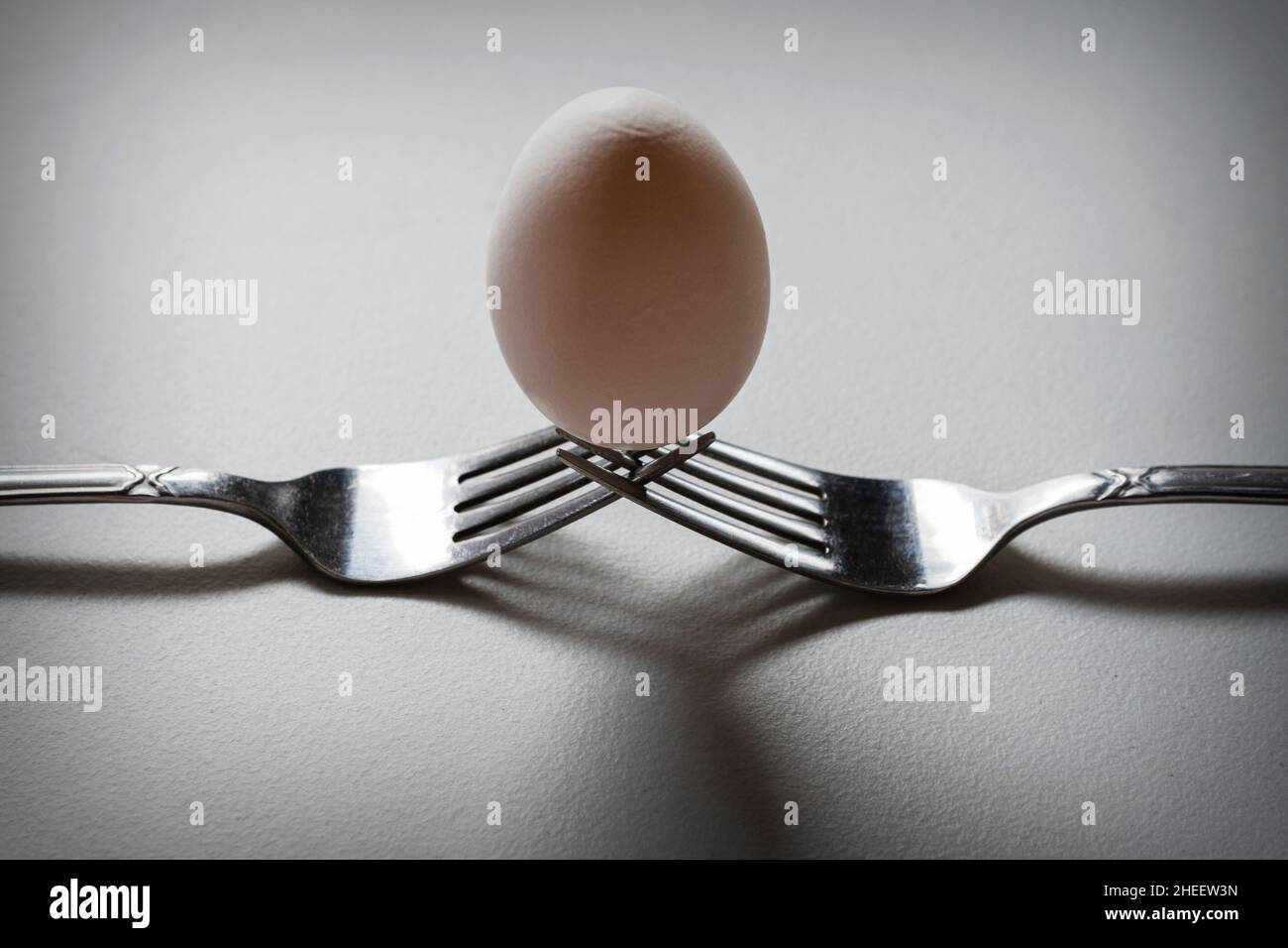 An egg balances on two forks. Soft backlighting Stock Photo - Alamy