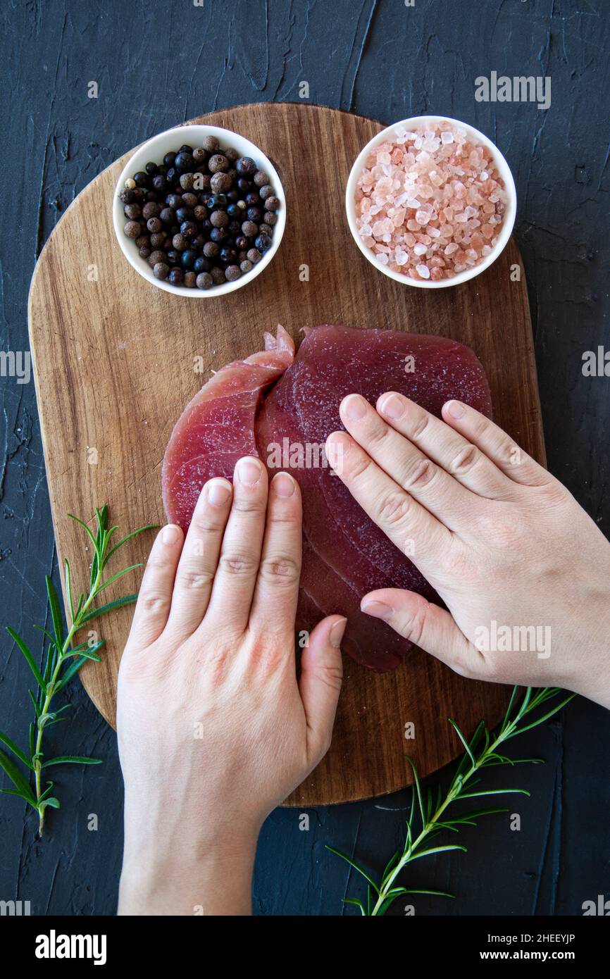 Steak tuna fish preparation on black stone background. Female hands and ...