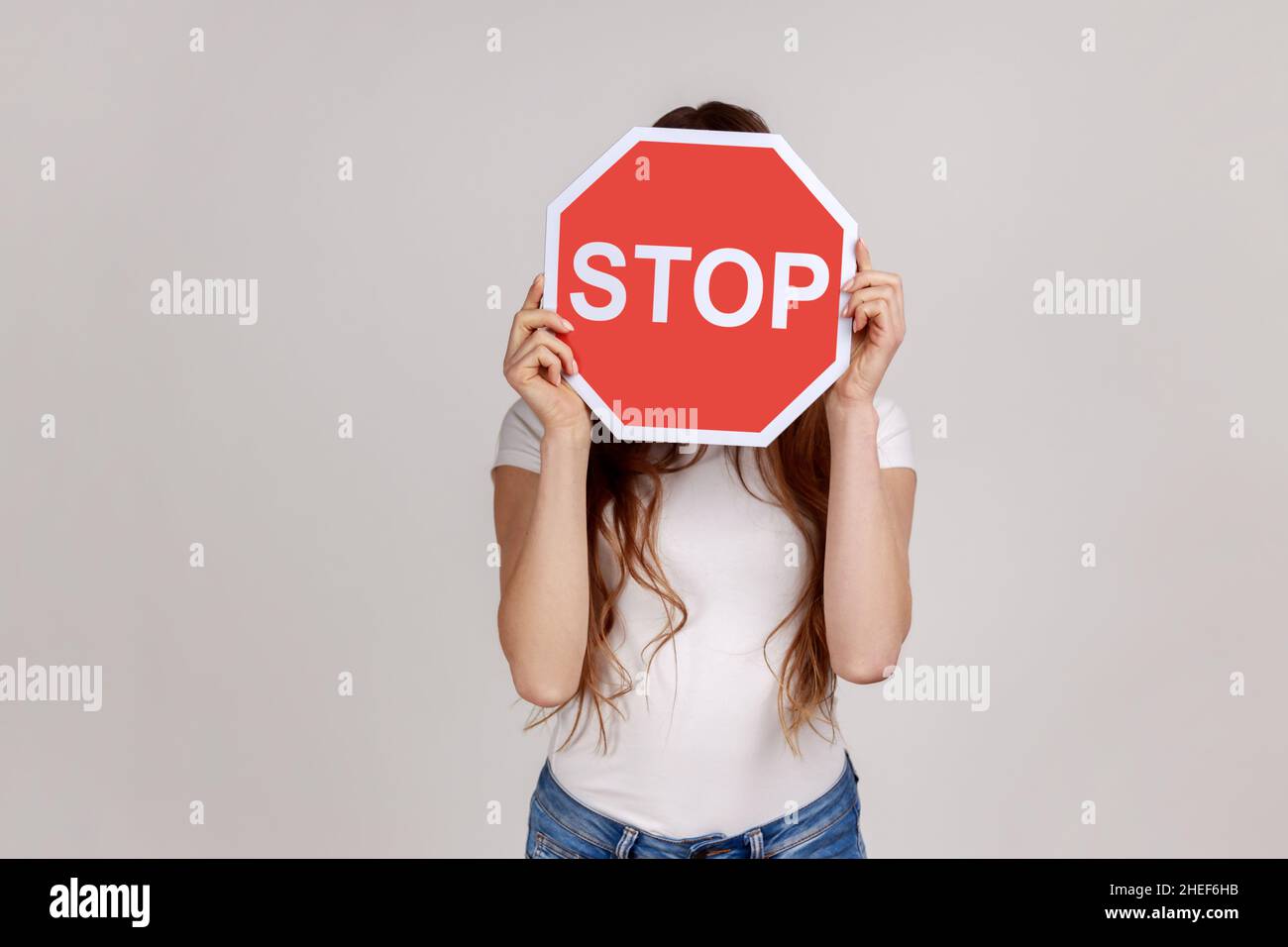 Unknown woman covering face with stop symbol, holding red traffic sign ...