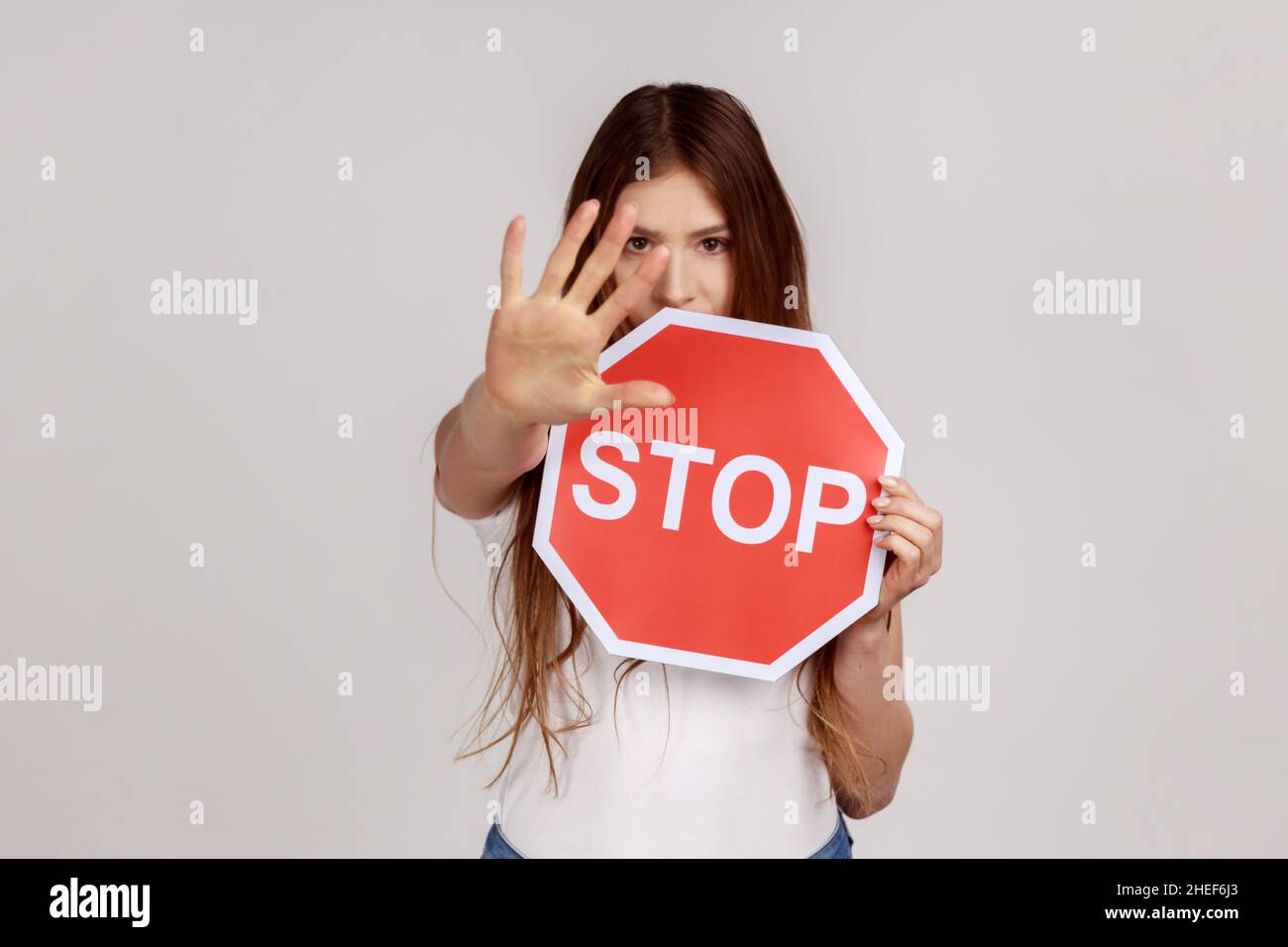 Strict bossy woman looking angrily and showing stop gesture, holding ...