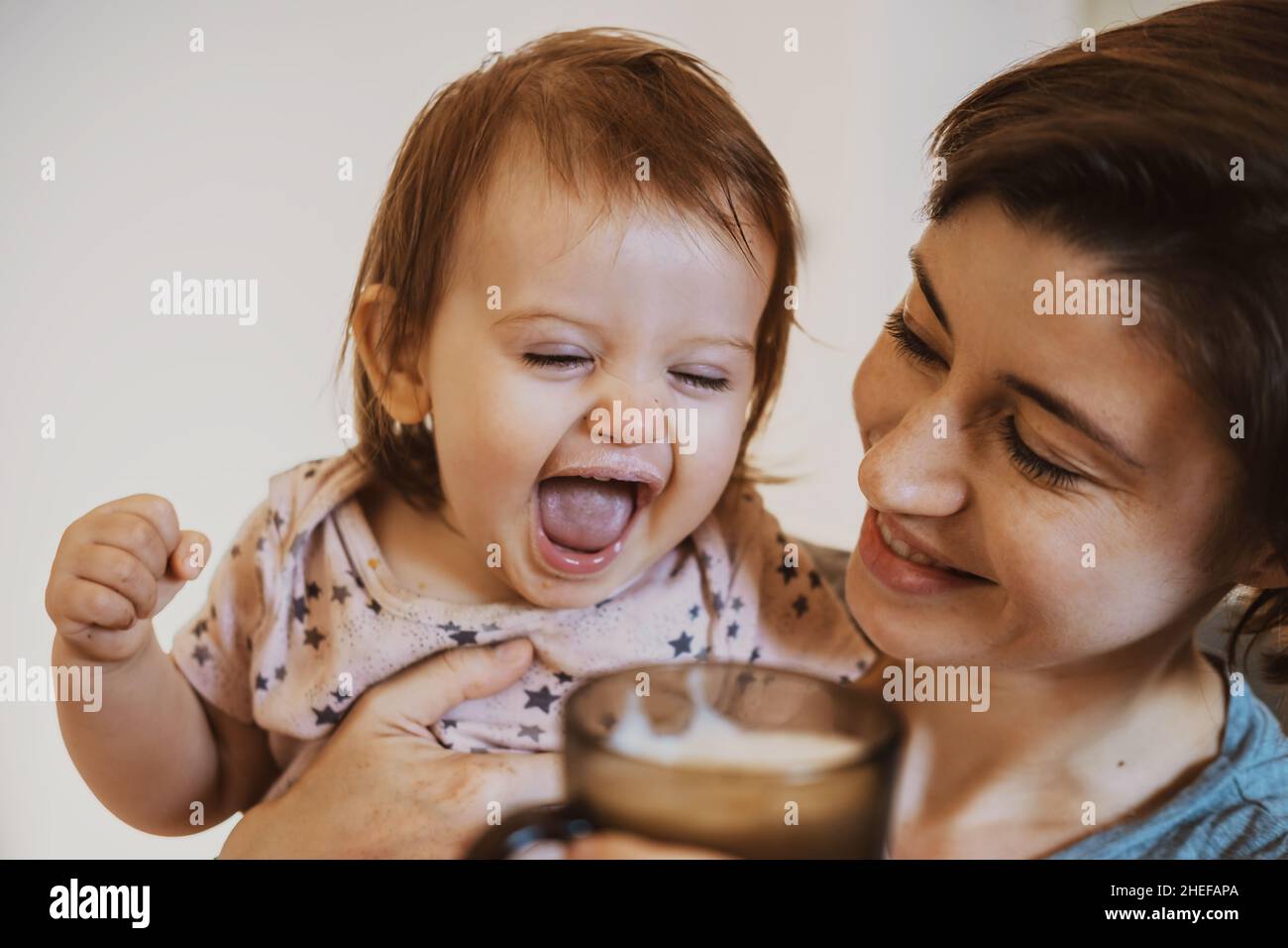 Closeup portrait of a mother giving milk to her little daughter. Baby ...