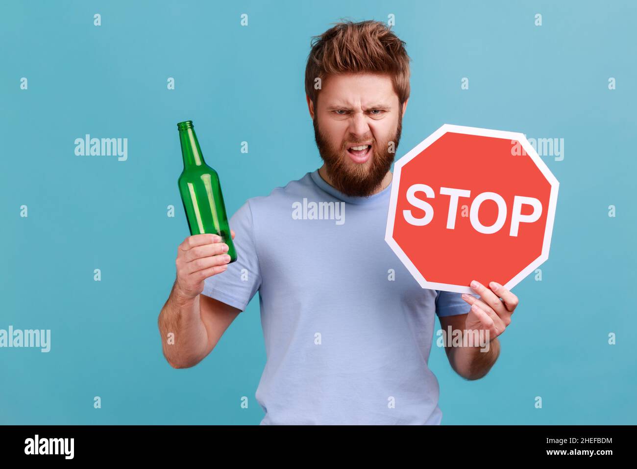 Portrait of bearded man showing alcoholic beverage beer bottle and stop ...