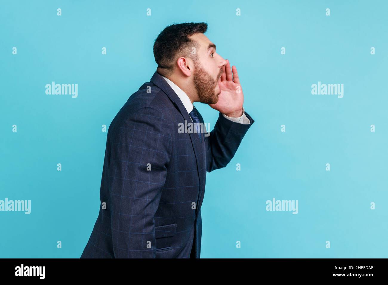 Side view of bearded man wearing official style suit loudly yelling ...